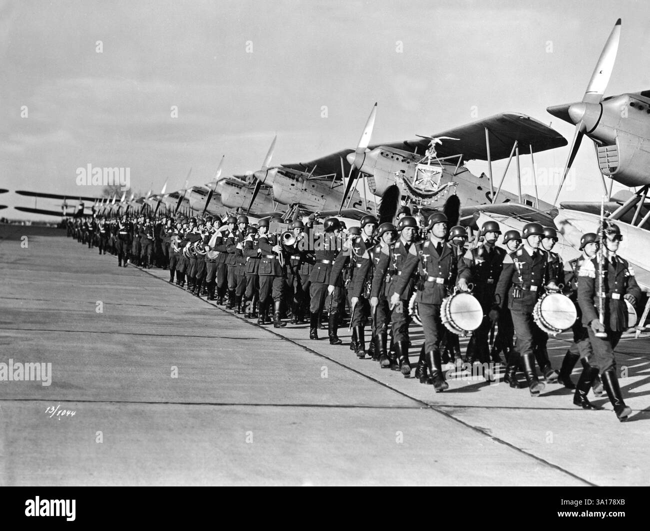 Luftwaffe marching band marches past a parked Heinkel He 60. Presumably ...