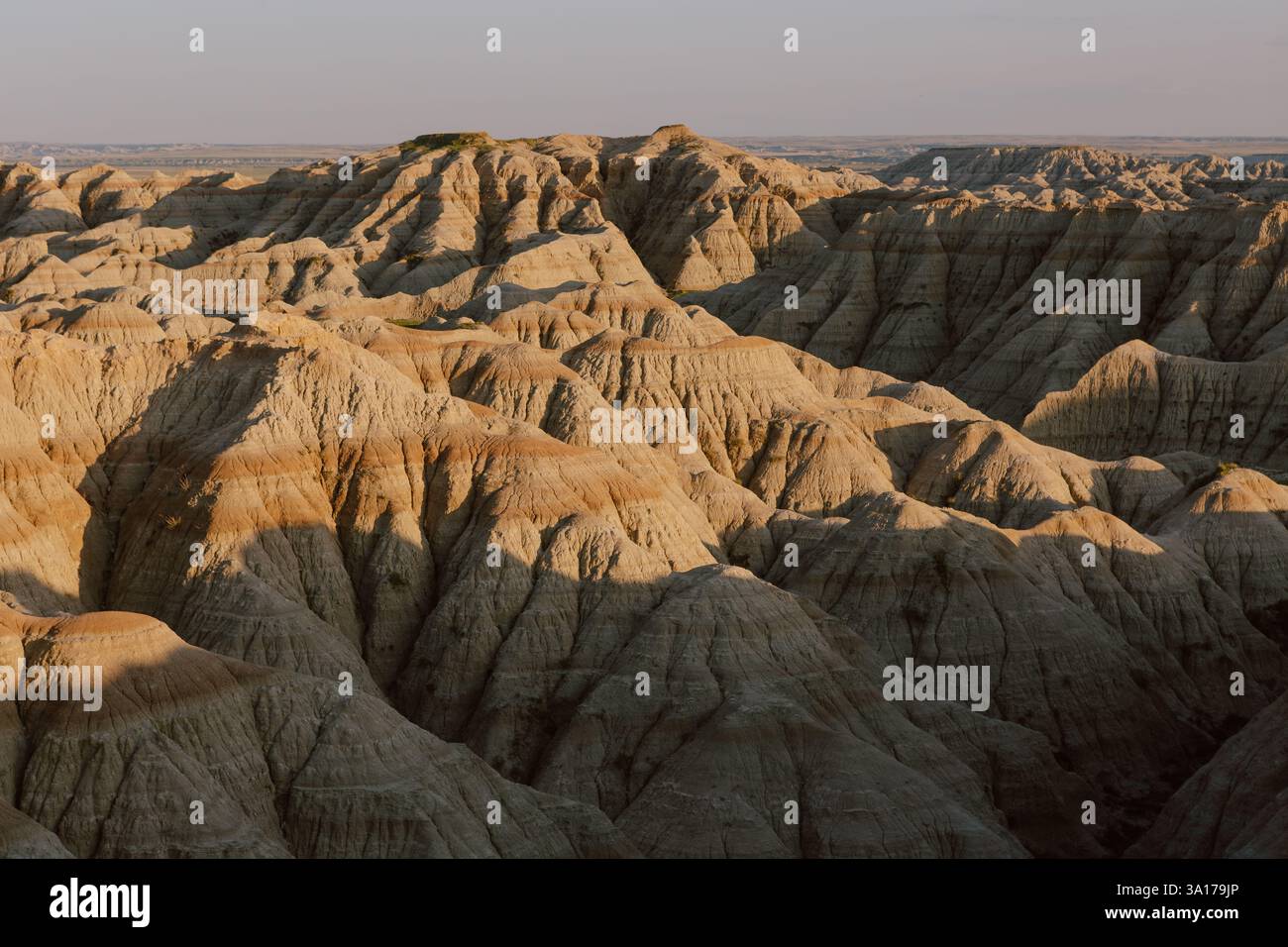 Rugged Badlands terrain with dramatic erosion and golden sunlight Stock Photo - Alamy