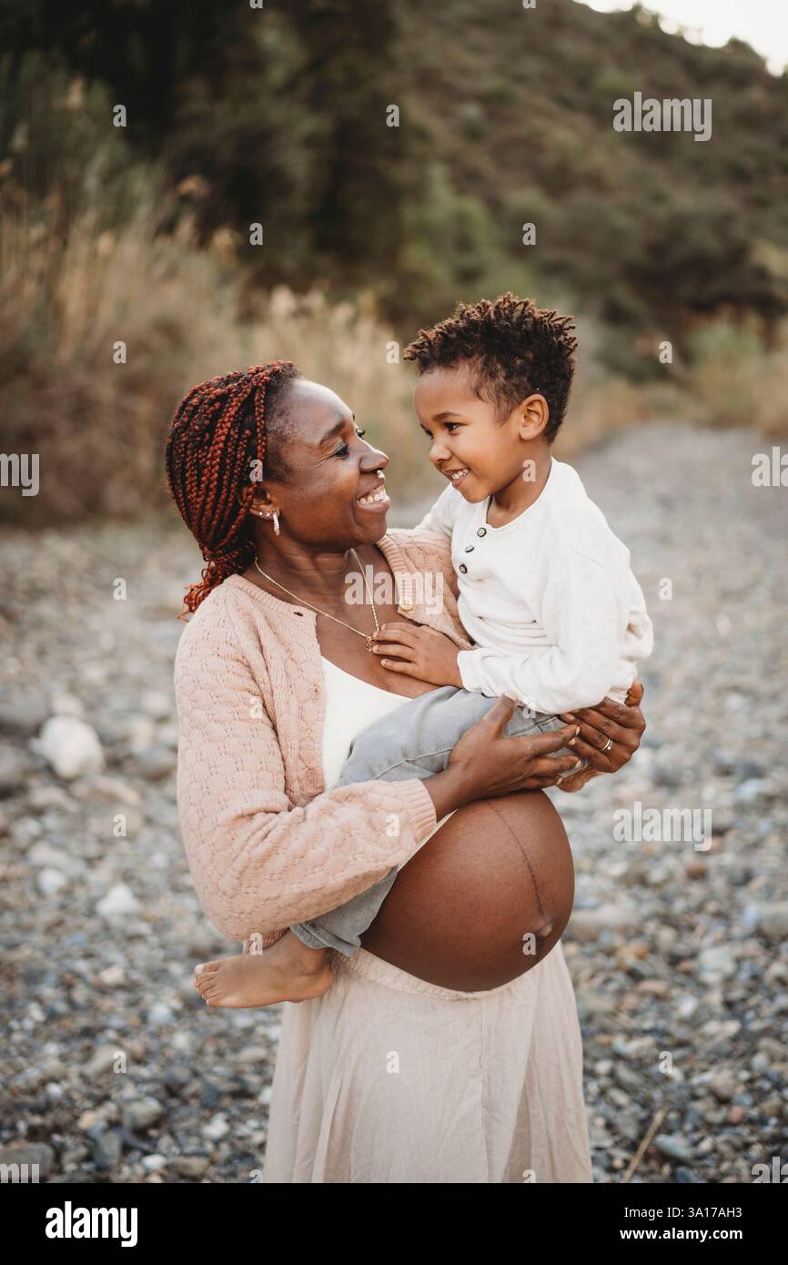 Smiling mix race boy sitting on black pregnant mom belly Stock Photo ...