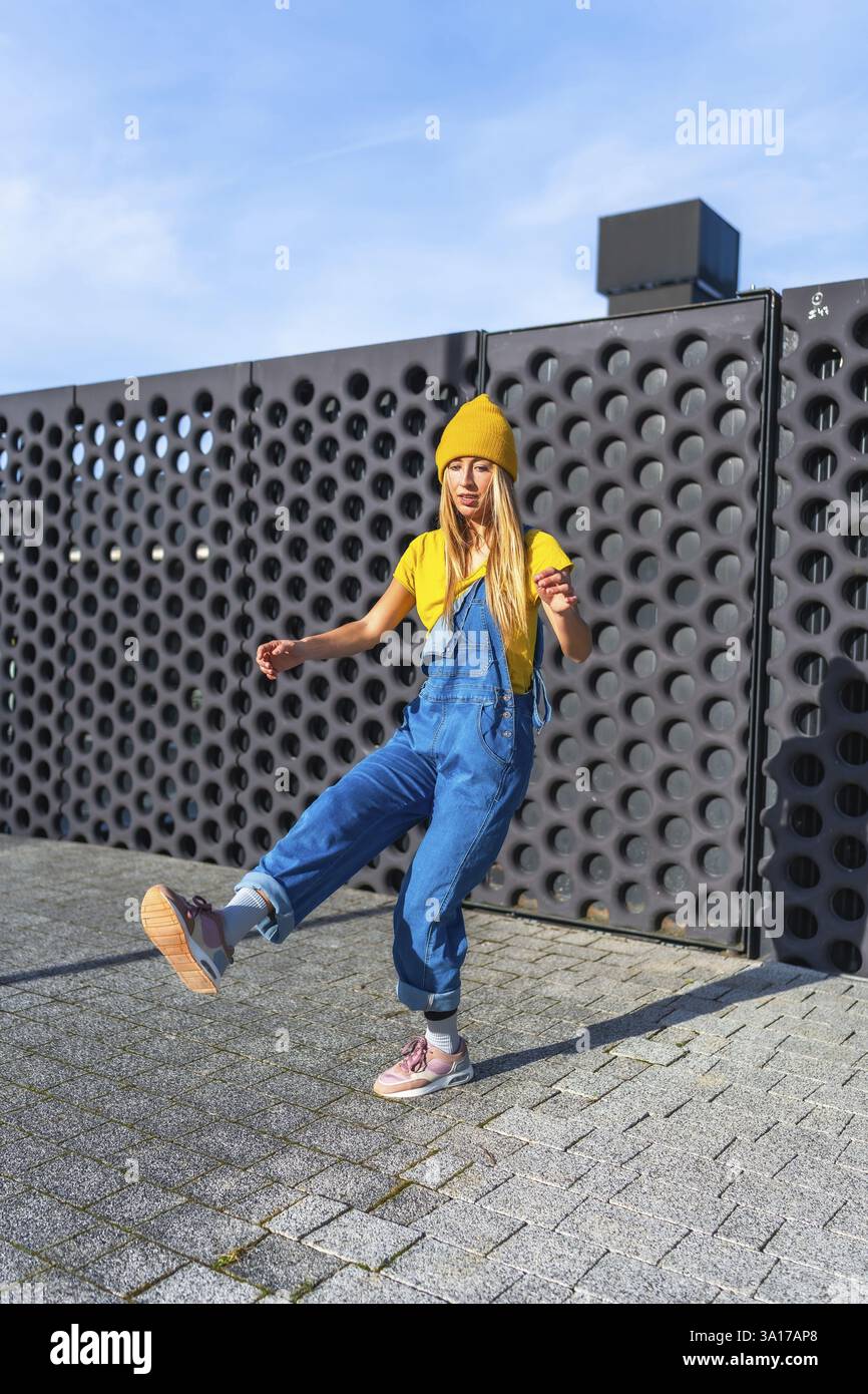 Urban dancer performing a street dance move outdoors, wearing a yellow ...