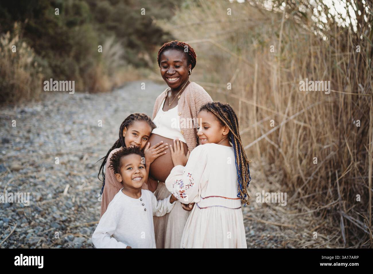 Black pregnant mother and mix race kids touching belly Stock Photo - Alamy