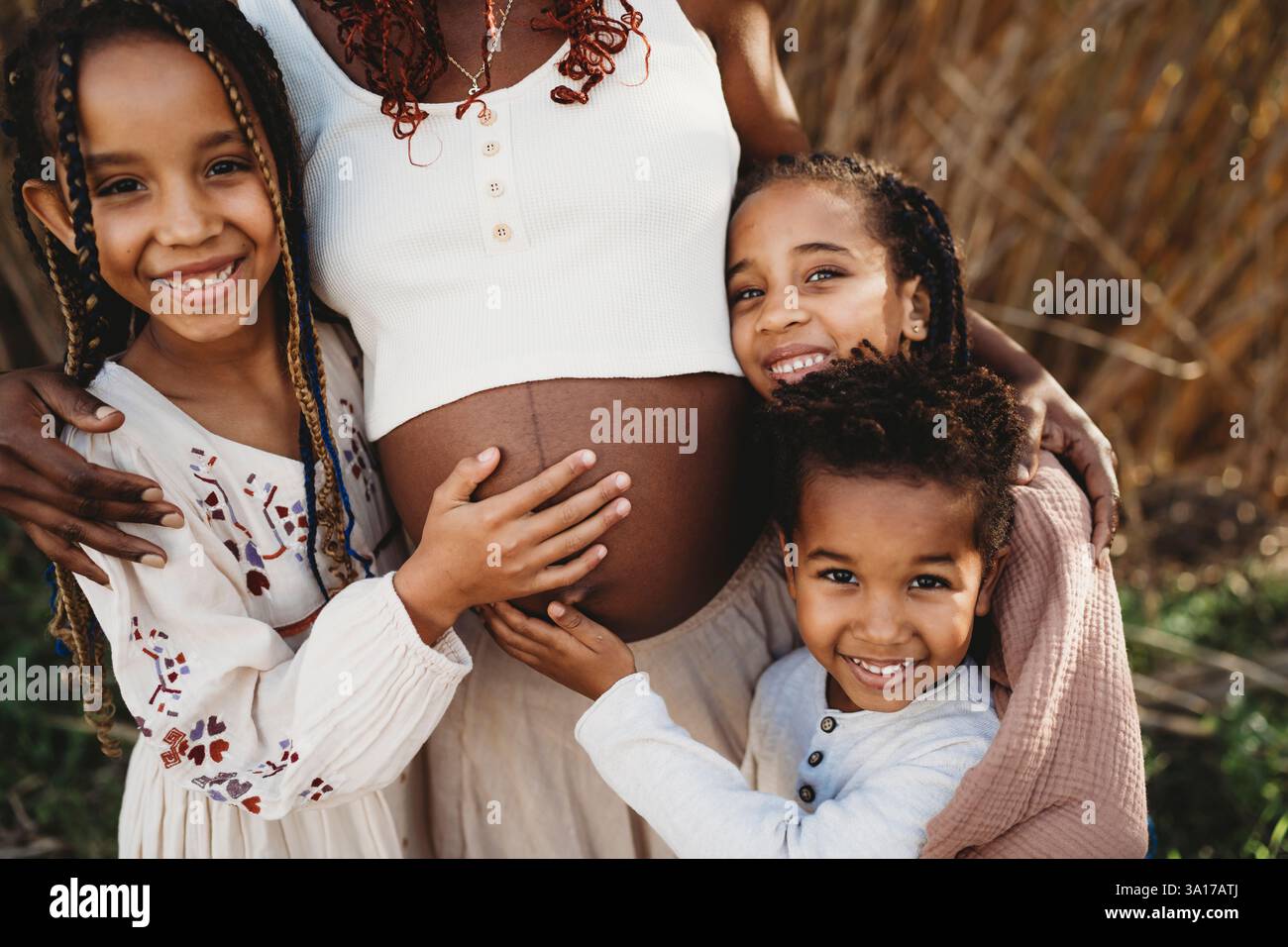 Mixed Race children hugging pregnant mom belly smiling Stock Photo - Alamy