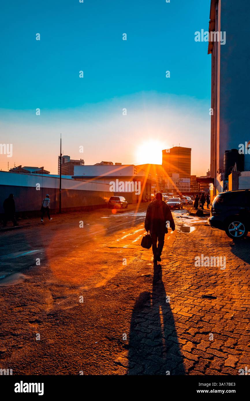 Harare man walking towards sunset Stock Photo - Alamy