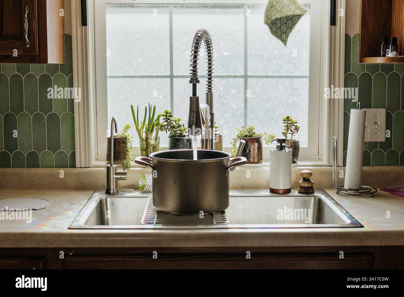 Water runs as soup pot is fill in kitchen sink near window Stock Photo ...