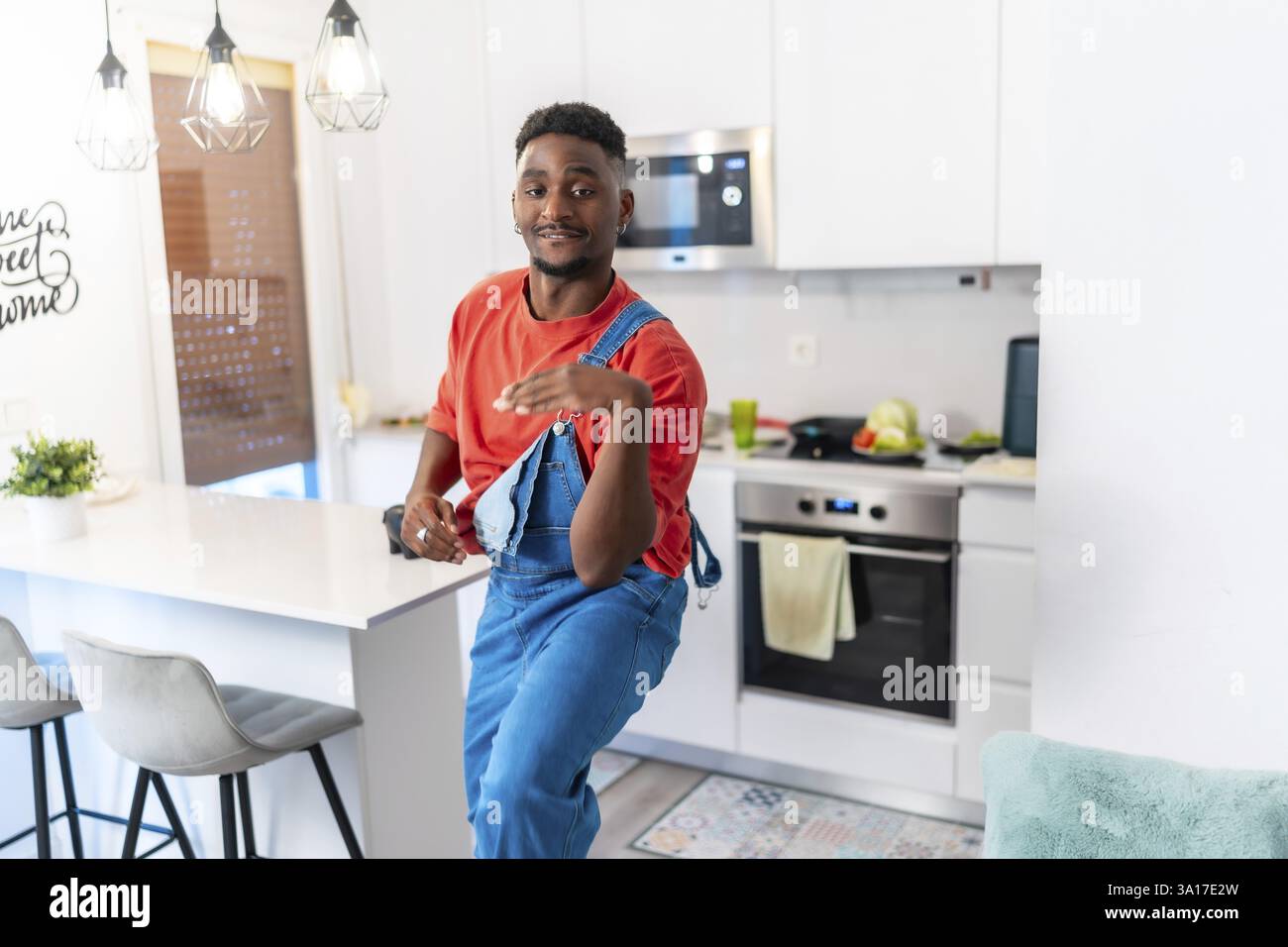 Young man dancing energetically in a modern, bright kitchen, expressing ...