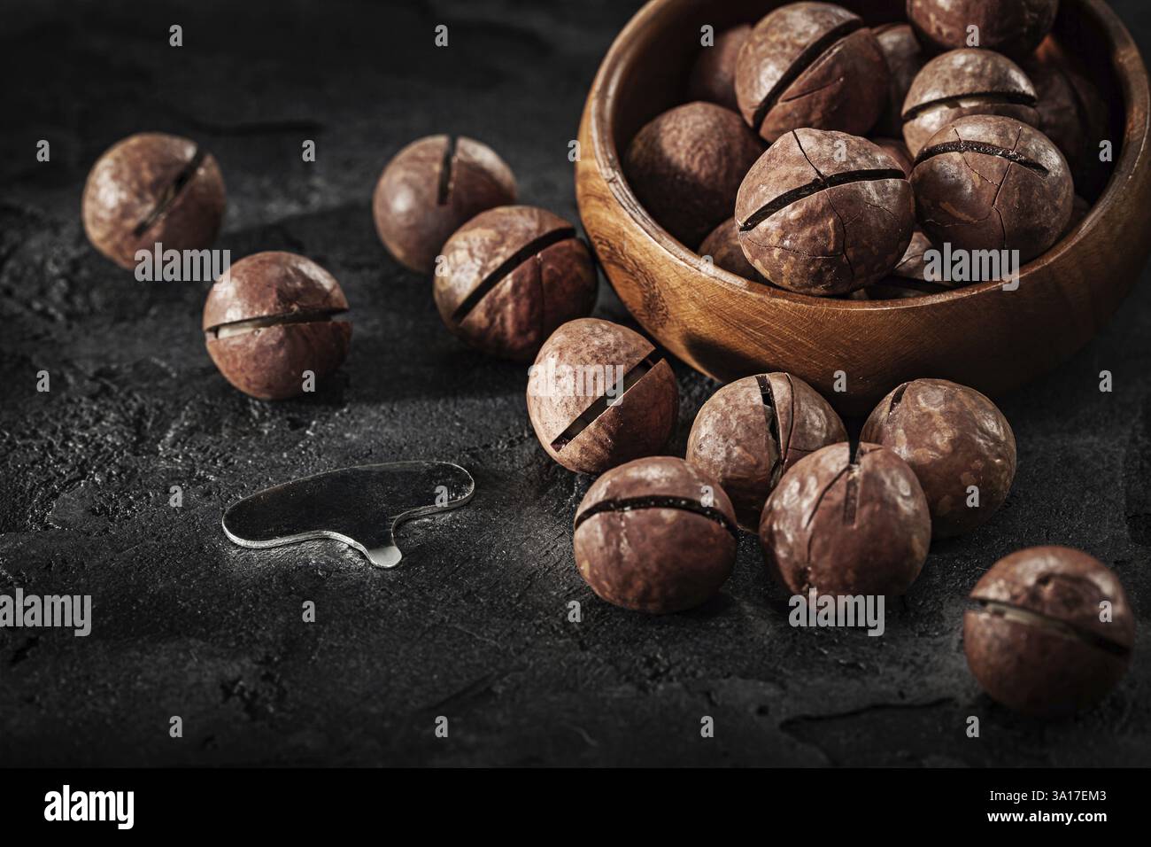 Macadamia Nuts And Key For Open It With Wooden Bowl On Black Background ...