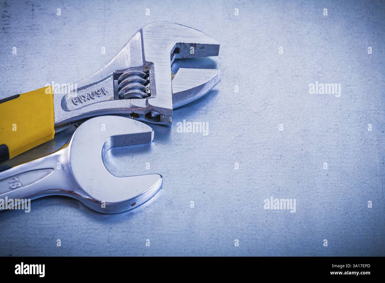Metallic background with adjustable spanner and hook wrench repairing ...