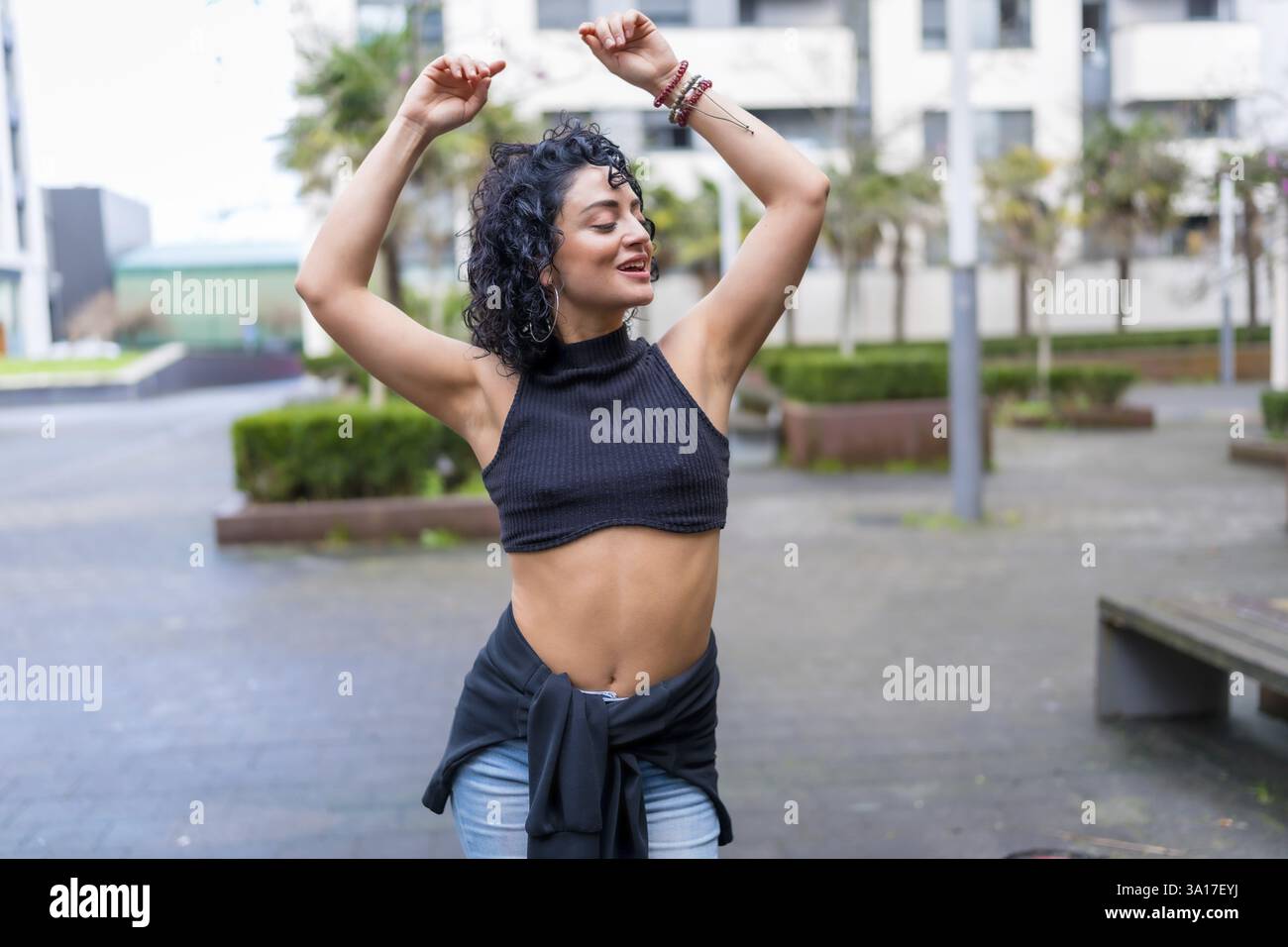 Curly haired woman dancing latin music in the urban park, enjoying ...