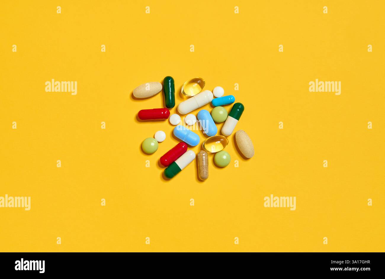 Various pills of different colors and shapes over yellow background ...
