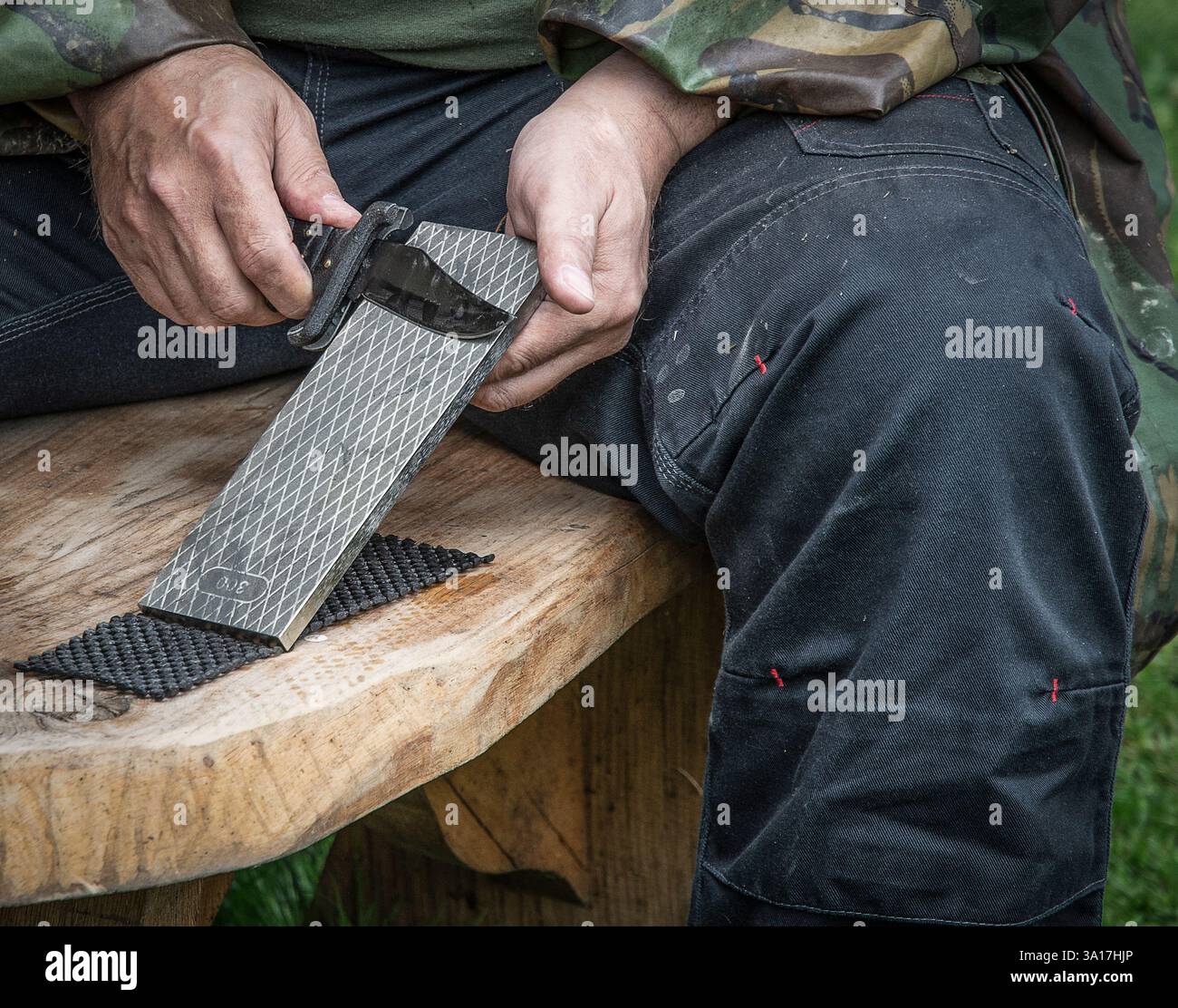 An Outdoor craftsman sharpening his knife on a diamond sharpening stone ...