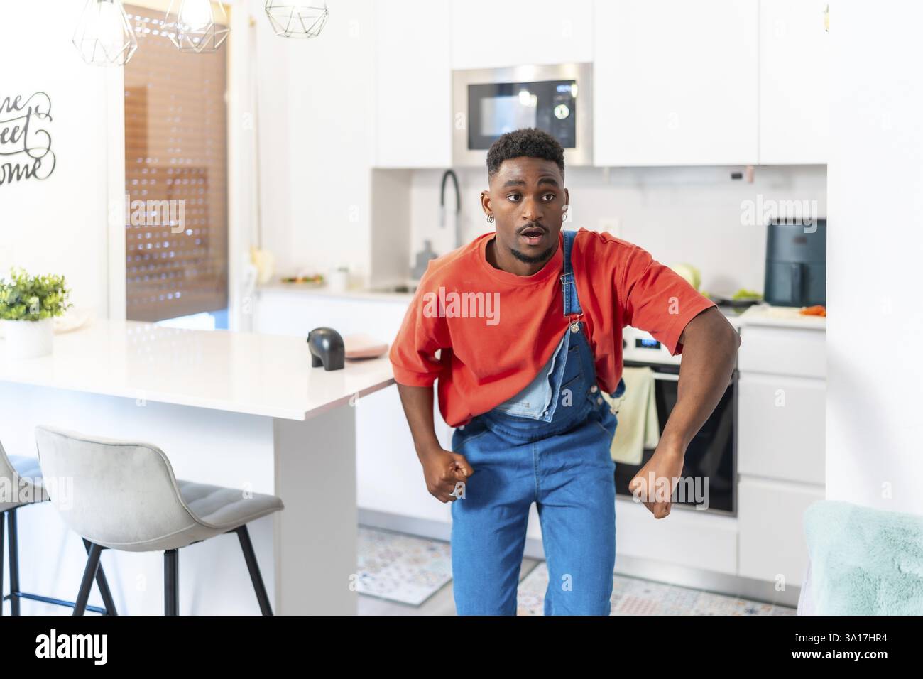 Energetic young dancer practicing urban dance moves in a modern kitchen ...