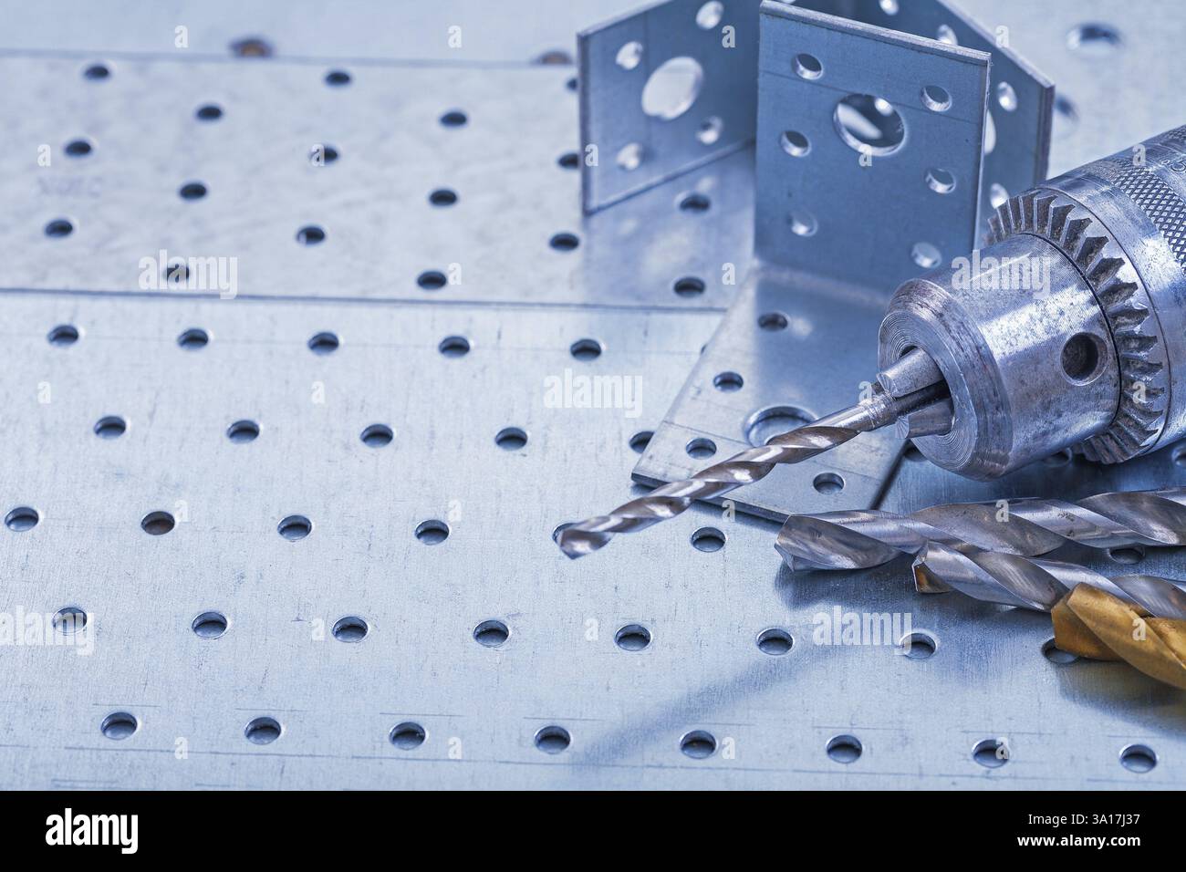 Drill with boring bits and angle bars on perforated metallic background ...