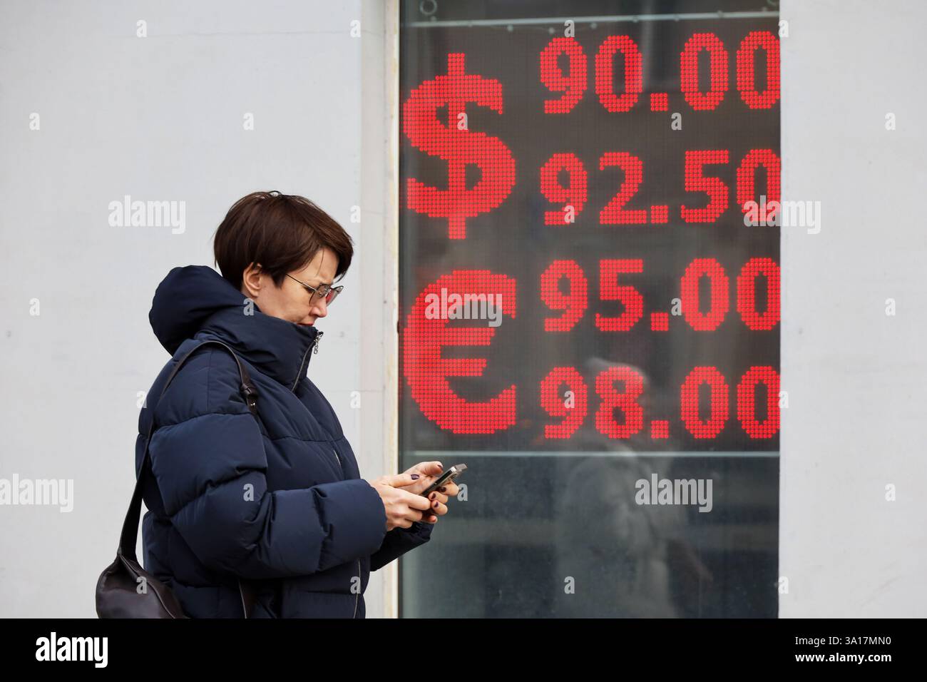 Woman with smartphone near the currency exchange office on city street ...