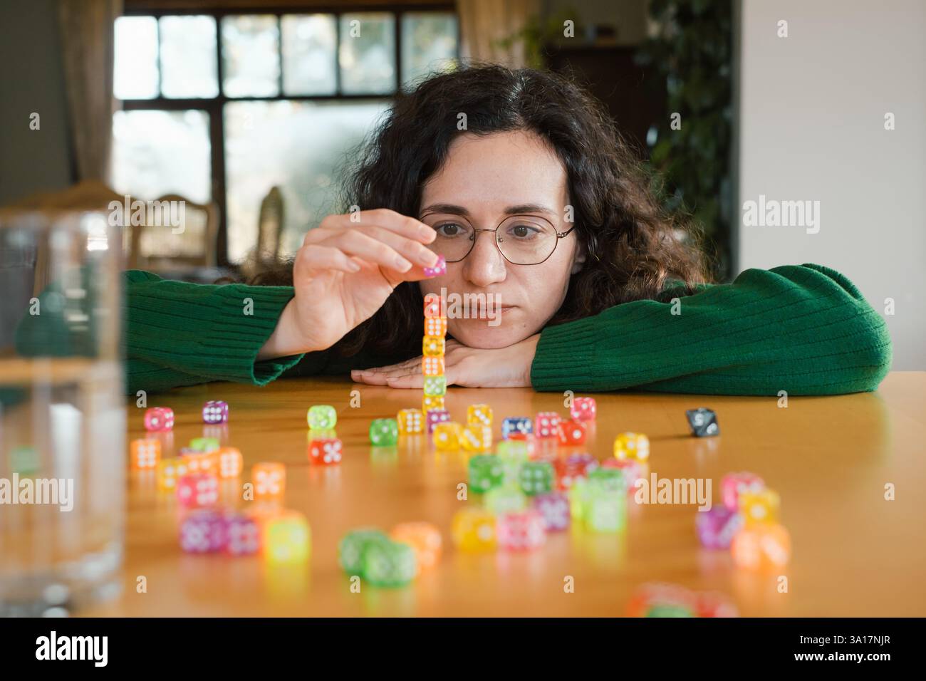 Woman player at her 40s stacking colorful dice during table game night ...