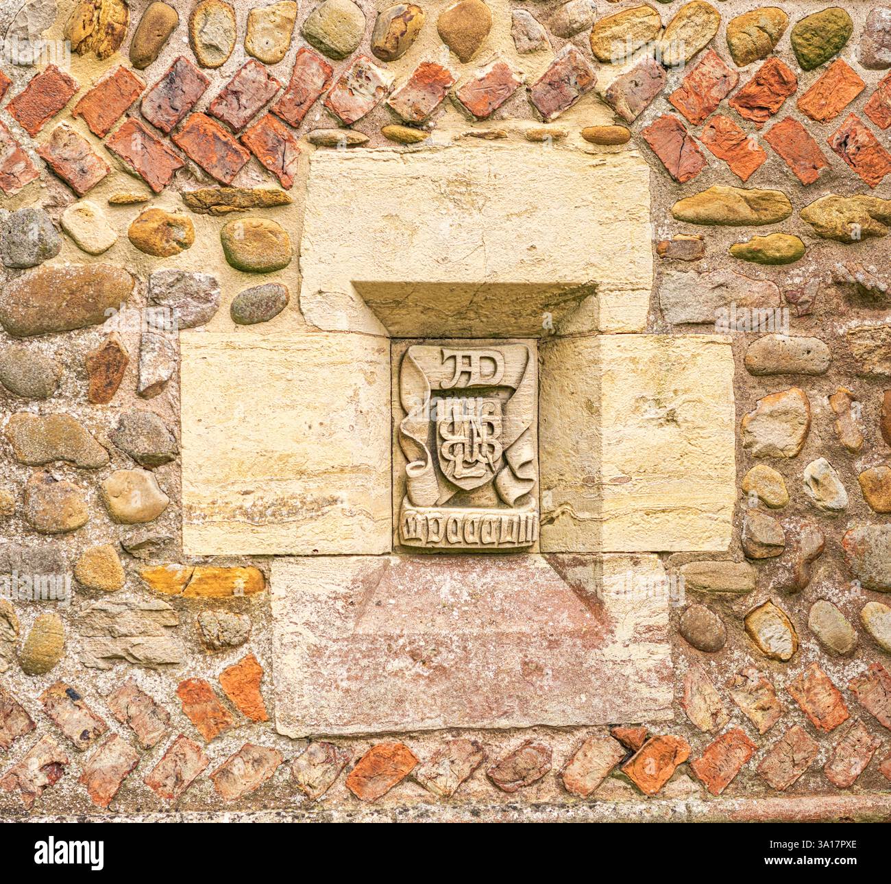 An emblem is set into a church with a sculpted scroll and a the date ...