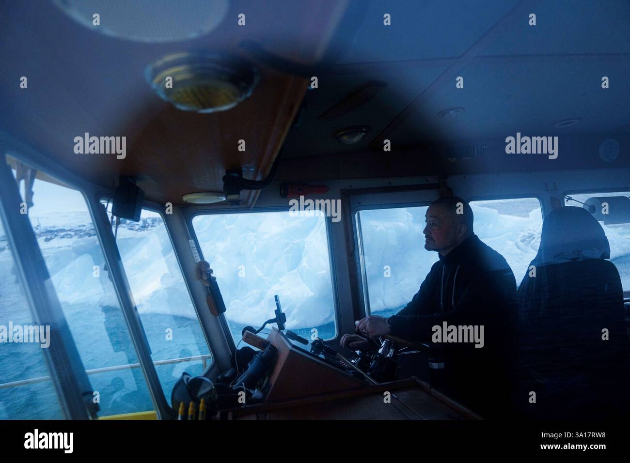 A boat captain rides though a frozen sea inlet outside of Nuuk ...