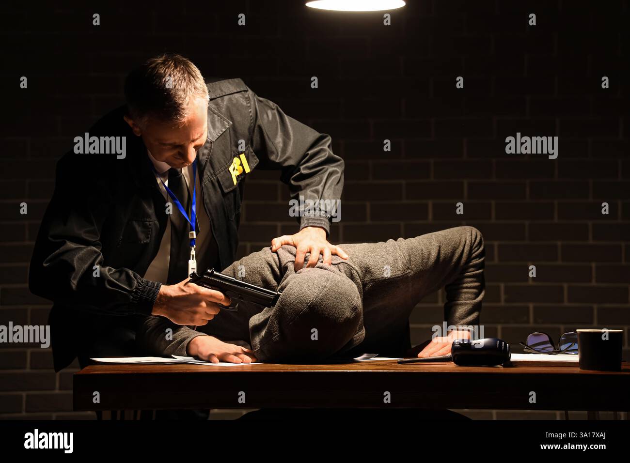 Mature FBI agent threatening suspect with gun in interrogation room ...