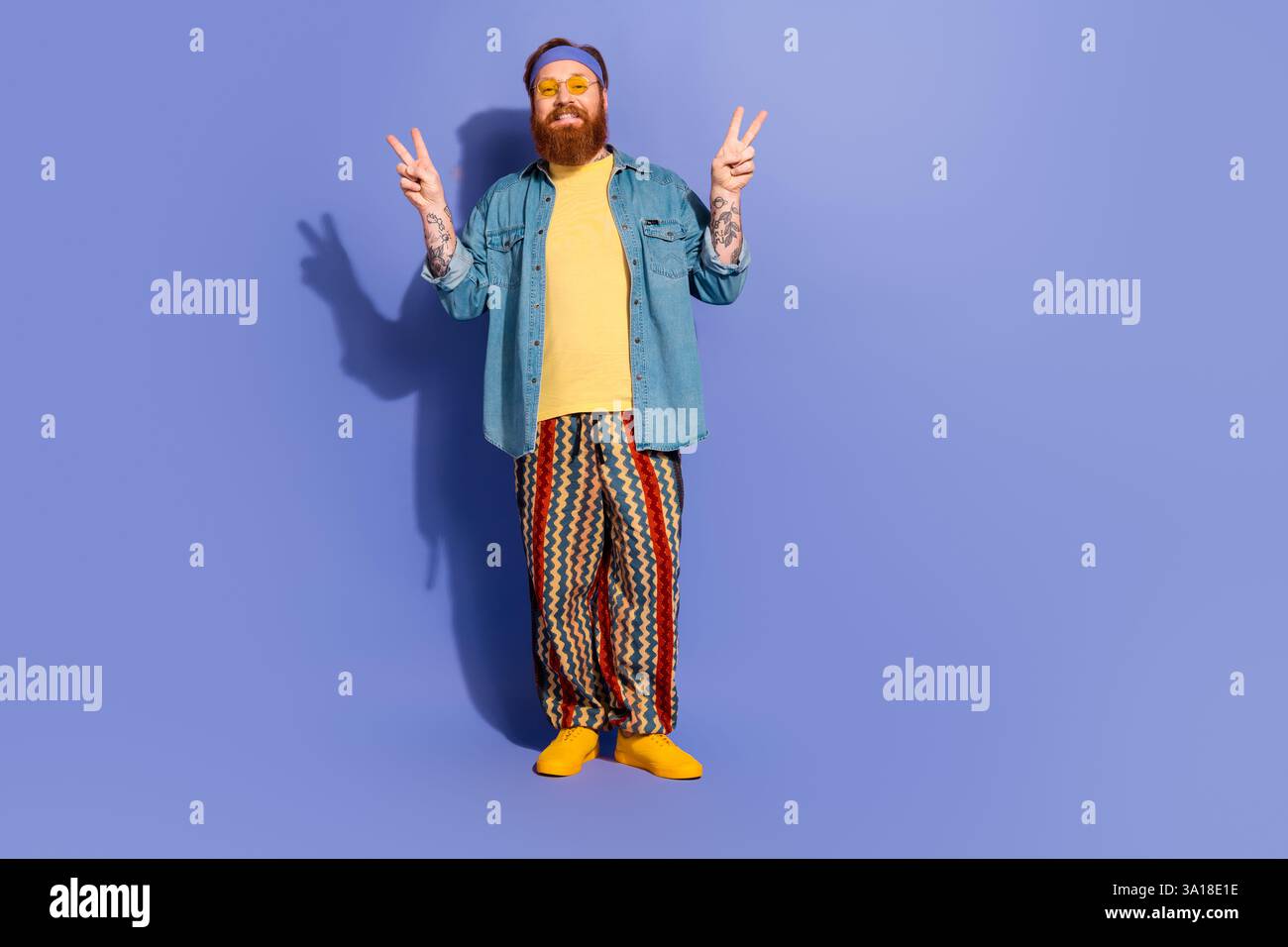 Happy stylish man with a beard flashing peace signs while enjoying a ...