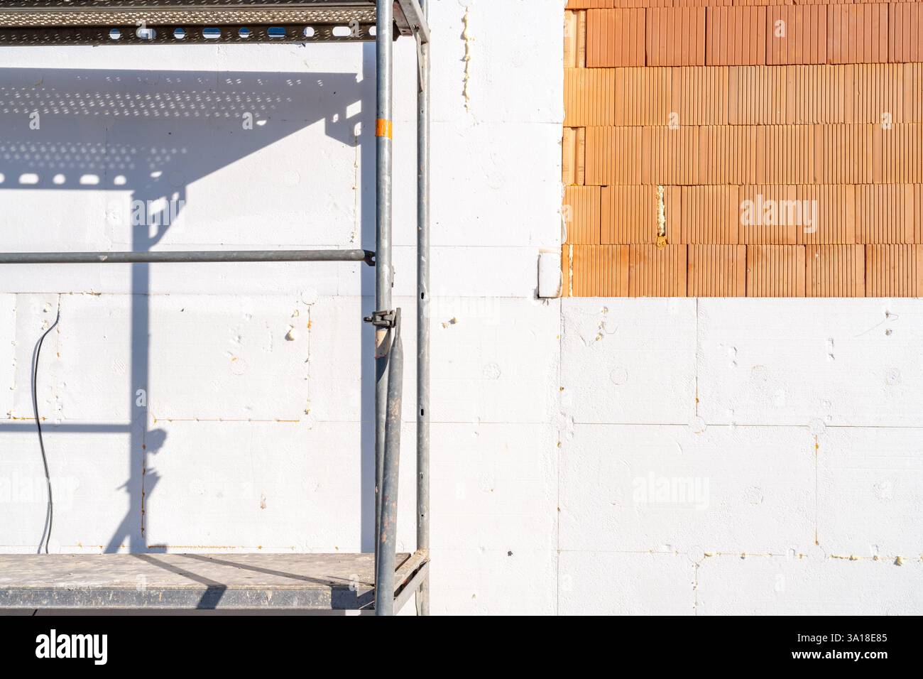 Scaffolding stands before insulated wall during building construction ...