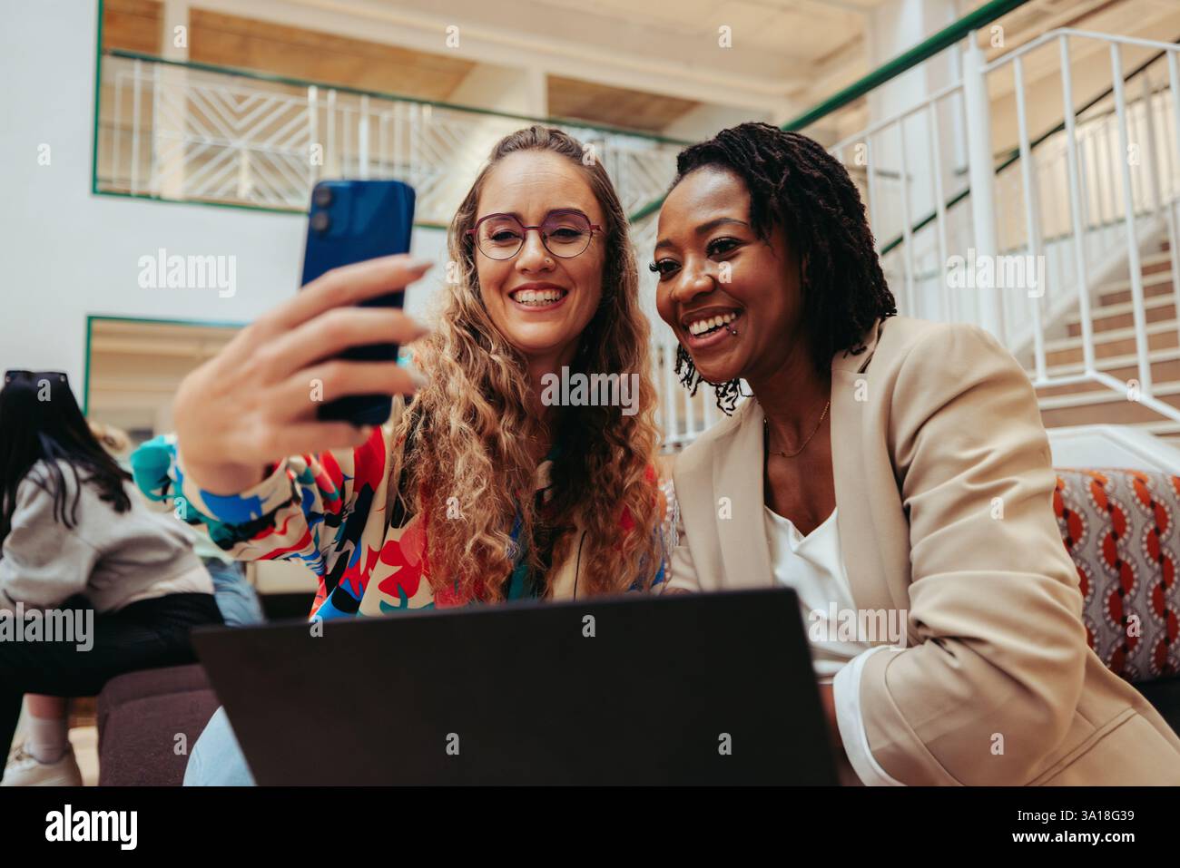 Two friendly coworkers from diverse backgrounds capture a happy moment ...