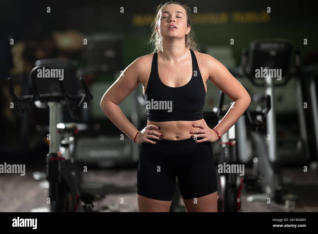 A fit woman strikes a confident pose in the gym after an intense ...