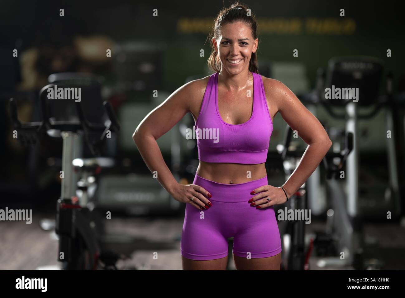 A fit woman strikes a confident pose in the gym after an intense ...