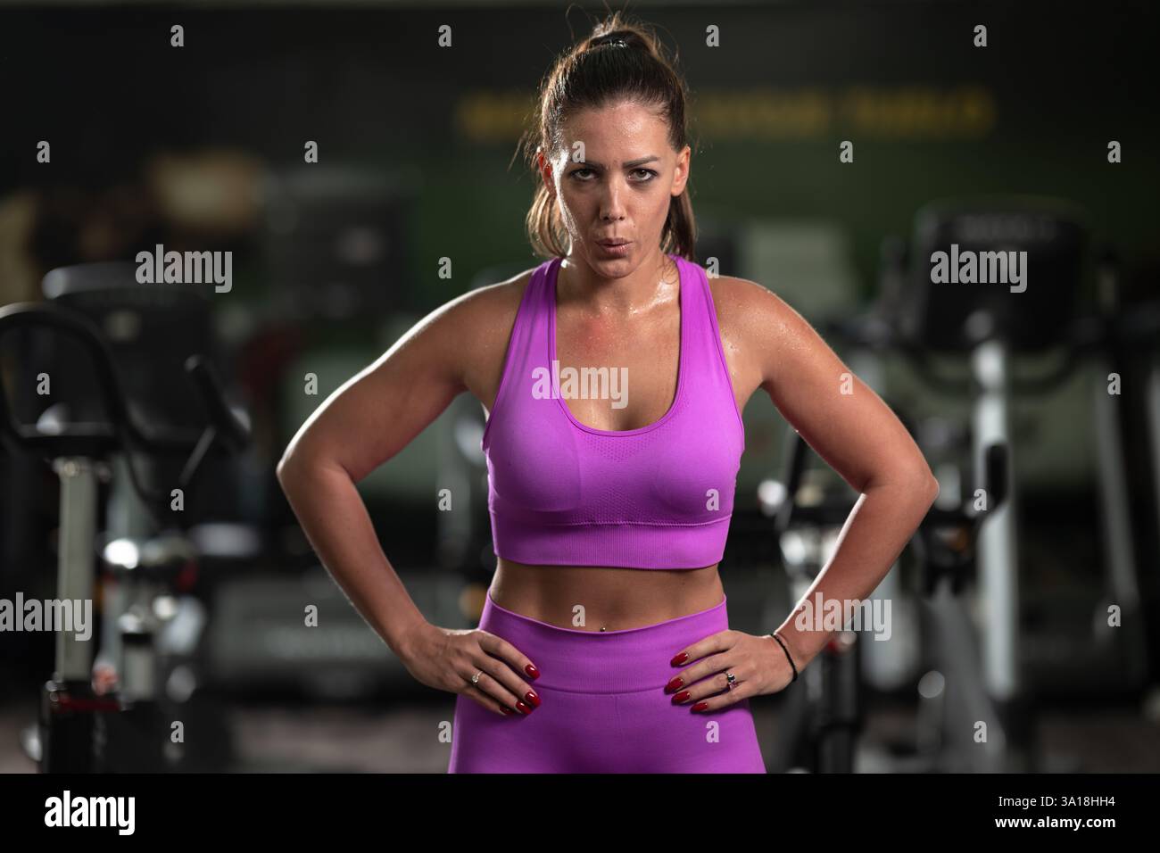 A fit woman strikes a confident pose in the gym after an intense ...