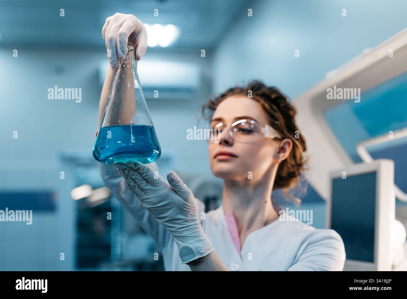 A scientist analyzes a blue liquid in a modern laboratory, close-up in ...