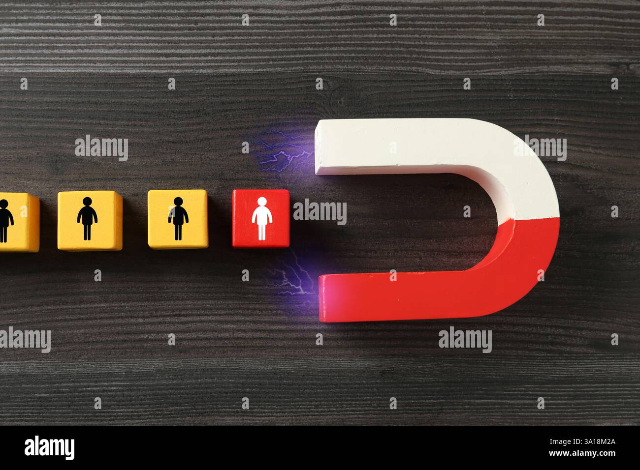 Magnet attracting cubes with human figures on wooden background, top ...