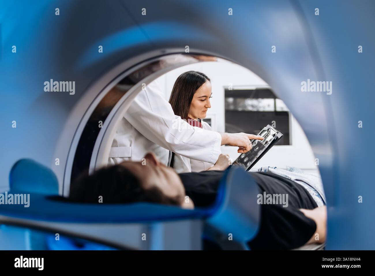 The patient lies inside an MRI or CT machine where the scan is ...