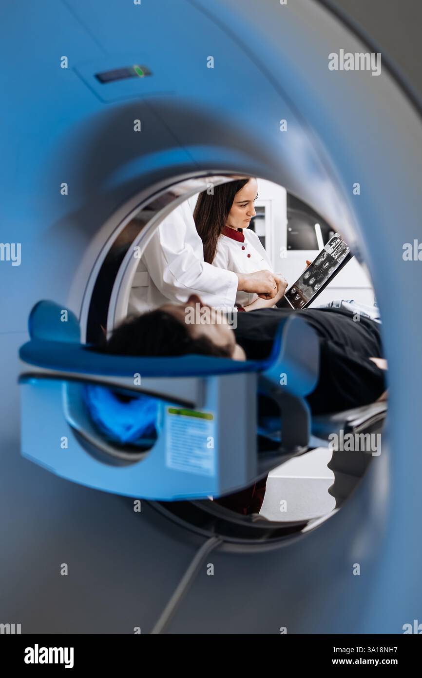 The patient lies inside an MRI or CT machine where the scan is performed. This high-tech ...