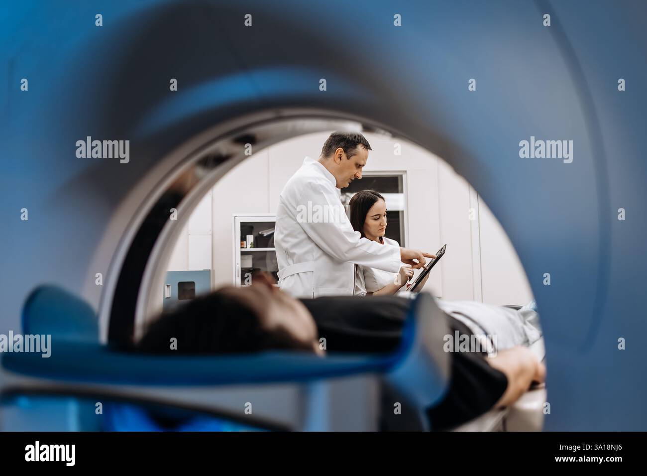 The patient lies inside an MRI or CT machine where the scan is performed. This high-tech ...
