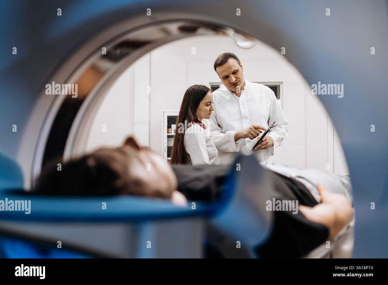 The patient lies inside an MRI or CT machine where the scan is performed. This high-tech ...