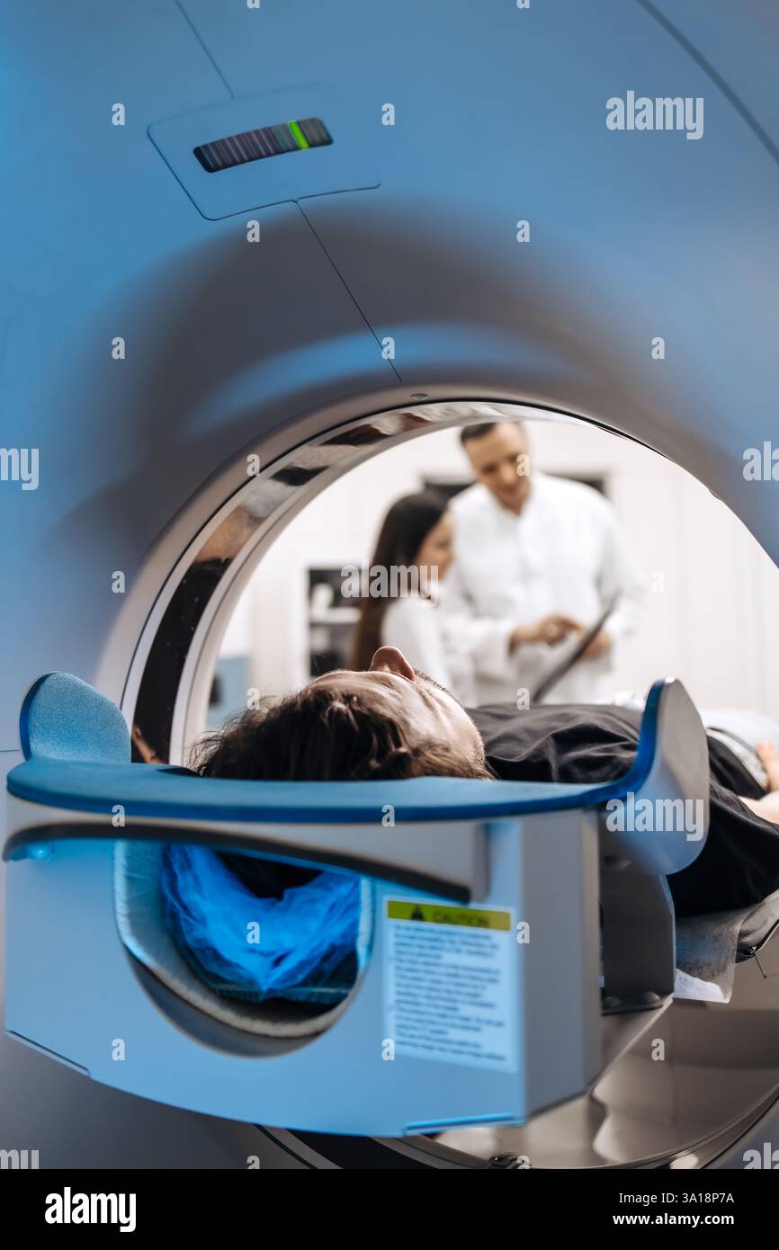 The patient lies inside an MRI or CT machine where the scan is performed. This high-tech ...