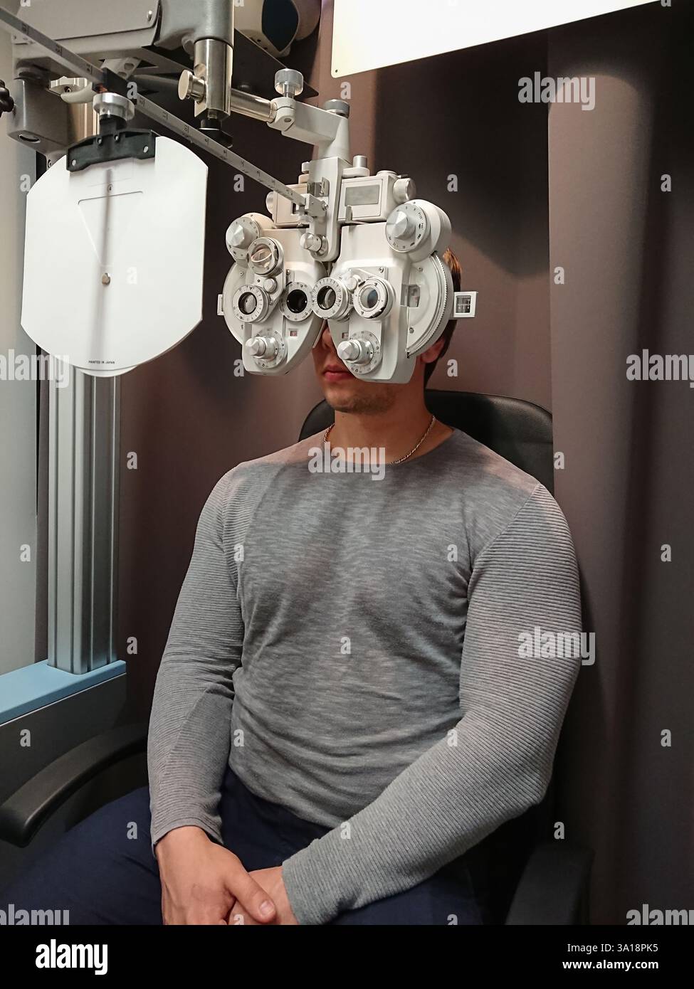 Man in professional clinic wearing phoropter for eye assessment, vision ...