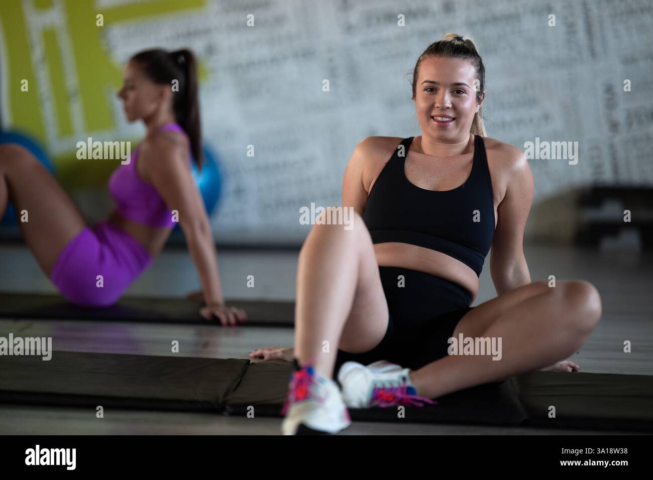Two fitness women resting and recovering in the gym after an intense ...