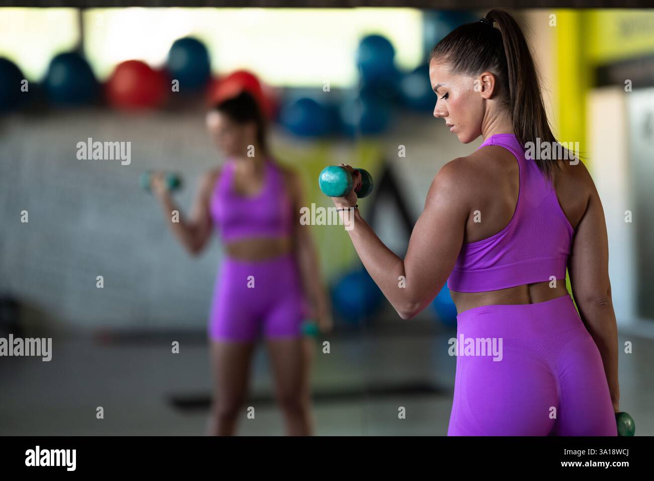 A focused and determined woman performs a strength building dumbbell ...