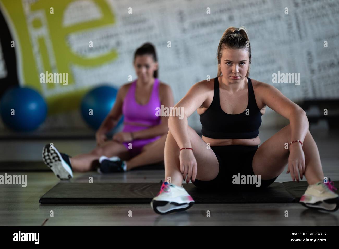 Two fitness women resting and recovering in the gym after an intense ...