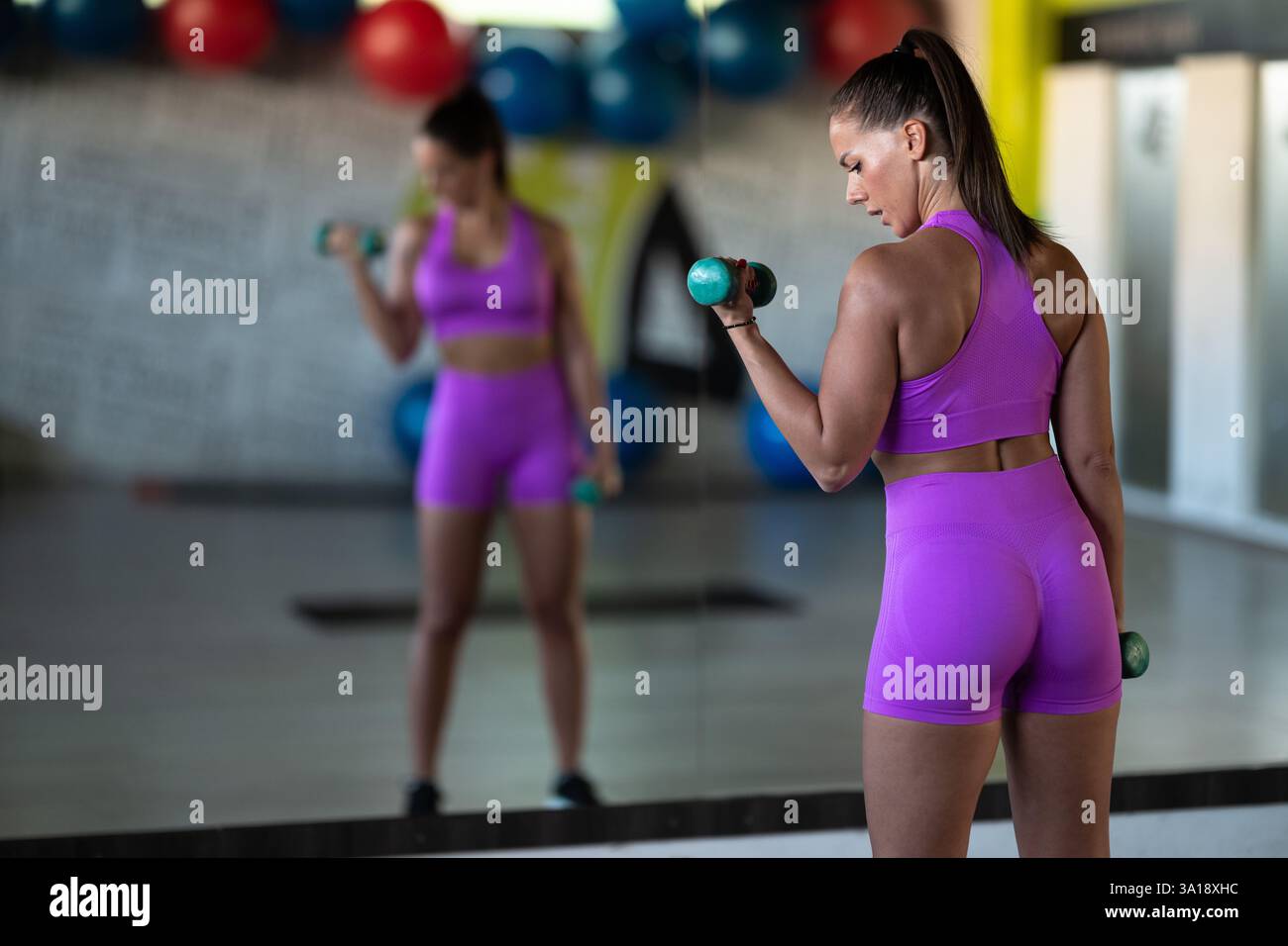 A focused and determined woman performs a strength building dumbbell ...