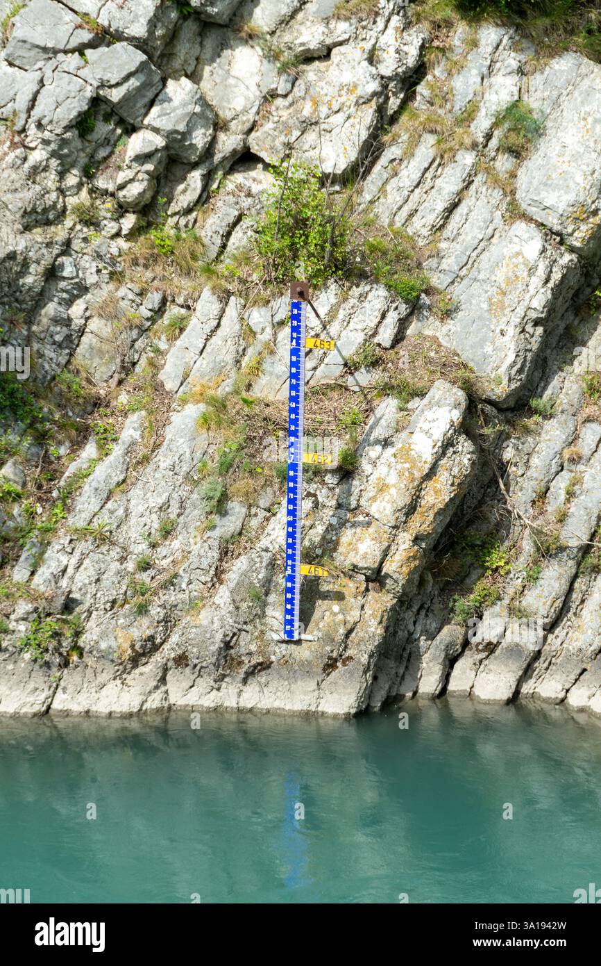 A water rise measurement gauge is attached to a rocky surface near a ...