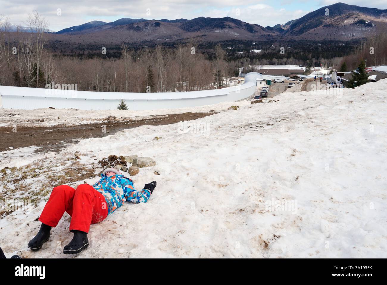 A young fans rest in the snow at the skeleton world championships ...