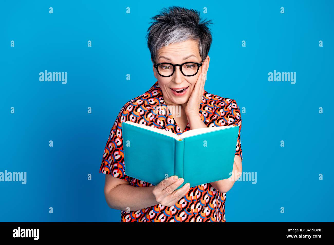 Charming Mature Woman Reading a Book with Surprise on Her Face Against ...
