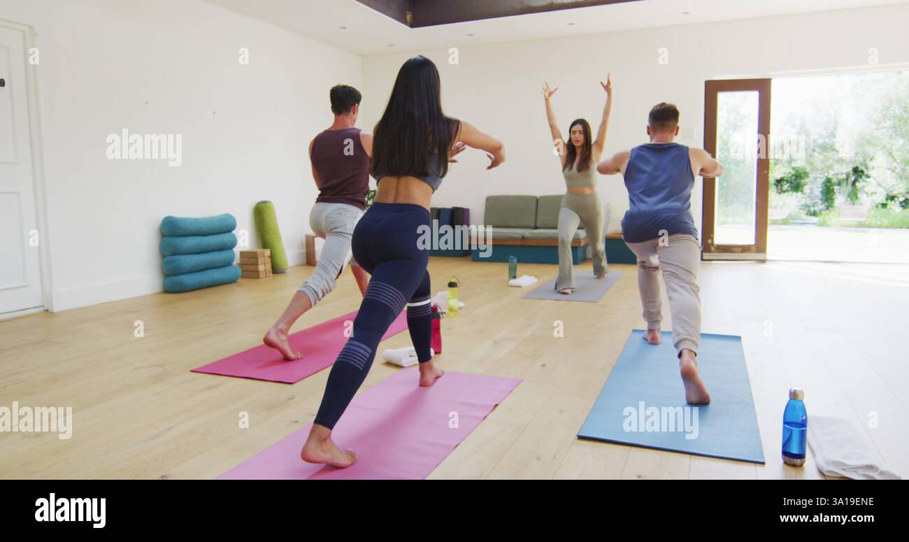 Caucasian female instructor demonstrating yoga poses to diverse group ...