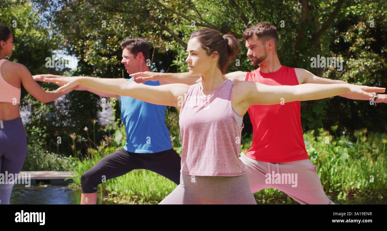 Diverse group practicing yoga pose in sunny park with asian female ...