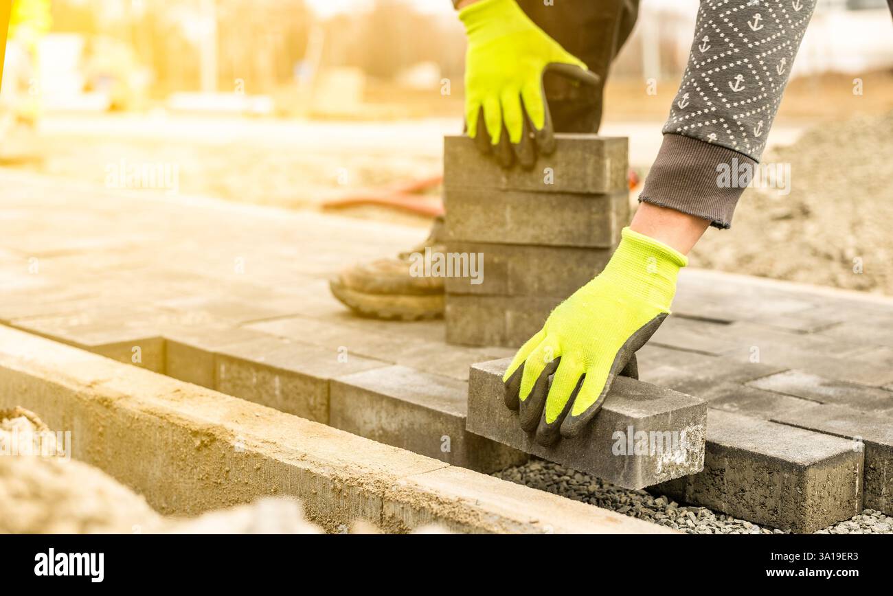 Construction worker paving a walkway with concrete or brick pavers ...