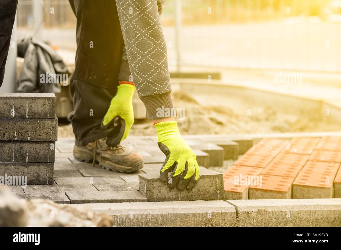 Construction worker carefully placing paving slabs for a new driveway ...