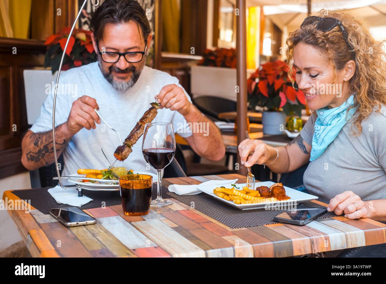 Cheerful tourist couple eating meat at a restaurant in Spain. Dating ...