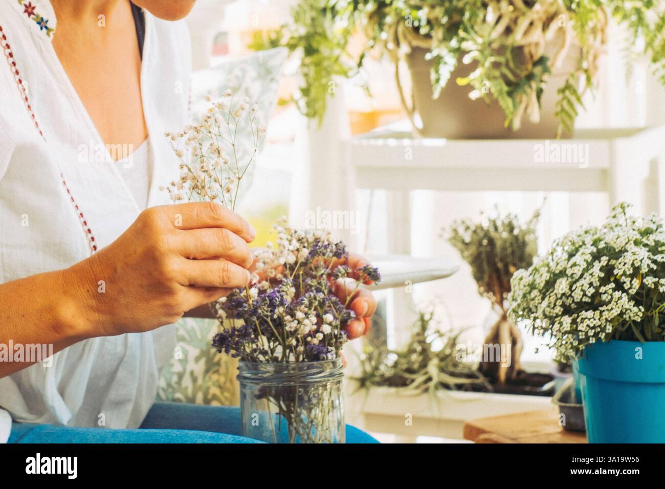 Beautiful lady takes care of her plants on the balcony. Sitting lady ...