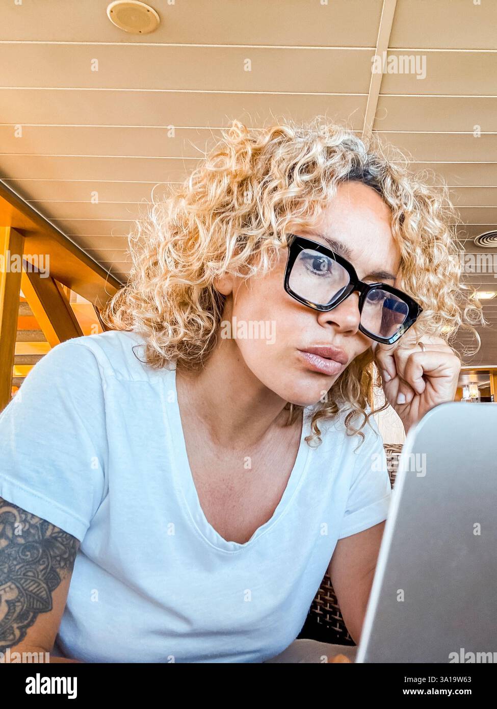 Beautiful blonde manager sitting at table during a ship trip. Woman ...