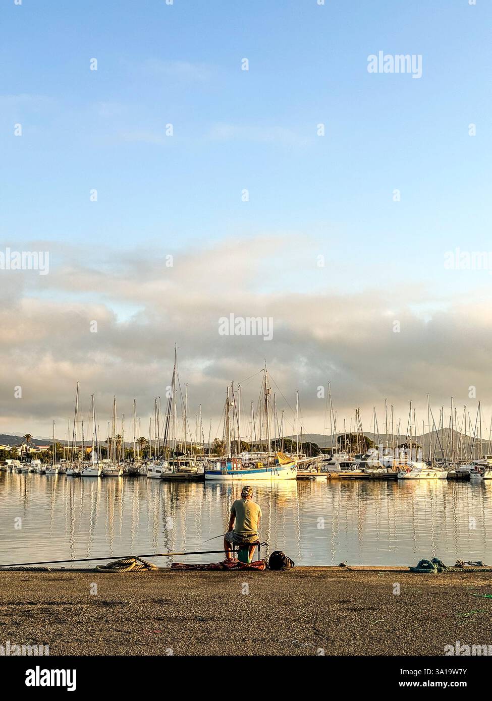 Back view of serene fisherman fishing at the harbour enjoying peaceful ...